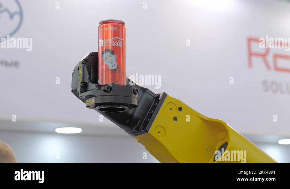 Industrial robotic arm rotating red Coca-Cola can at robot exhibition ...