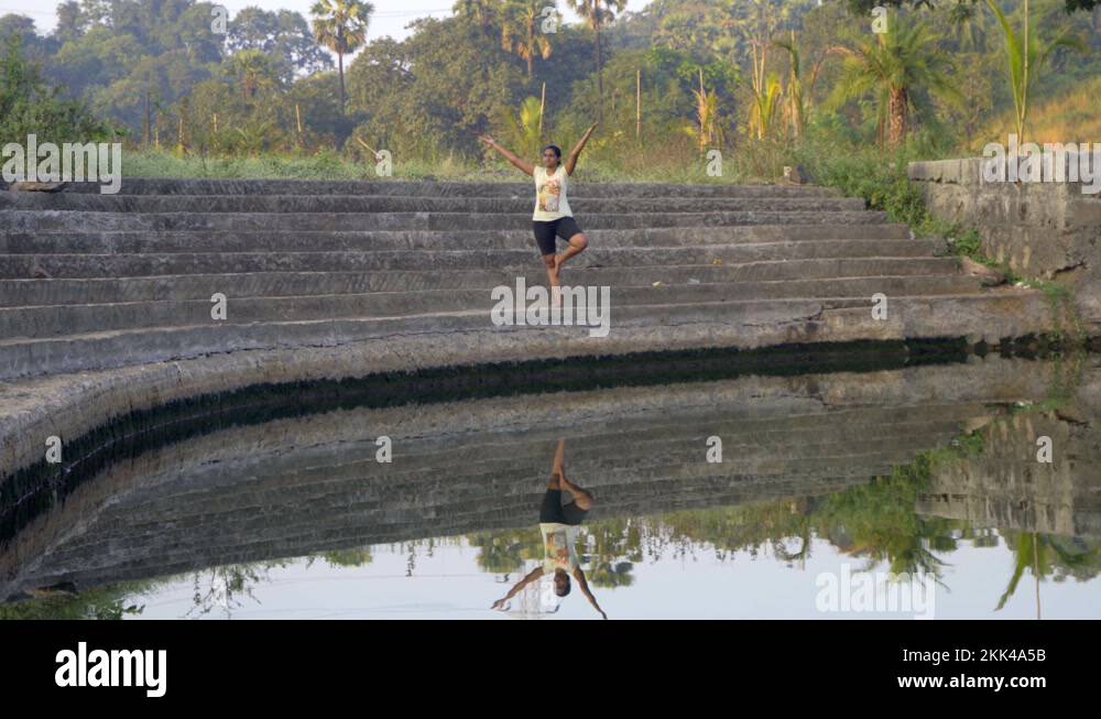 girl doing tree pose vrhsasana double image reflection in still water ...
