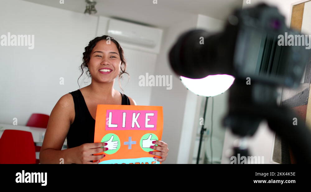 Girl talking to camera creating media channel showing sign to like and ...