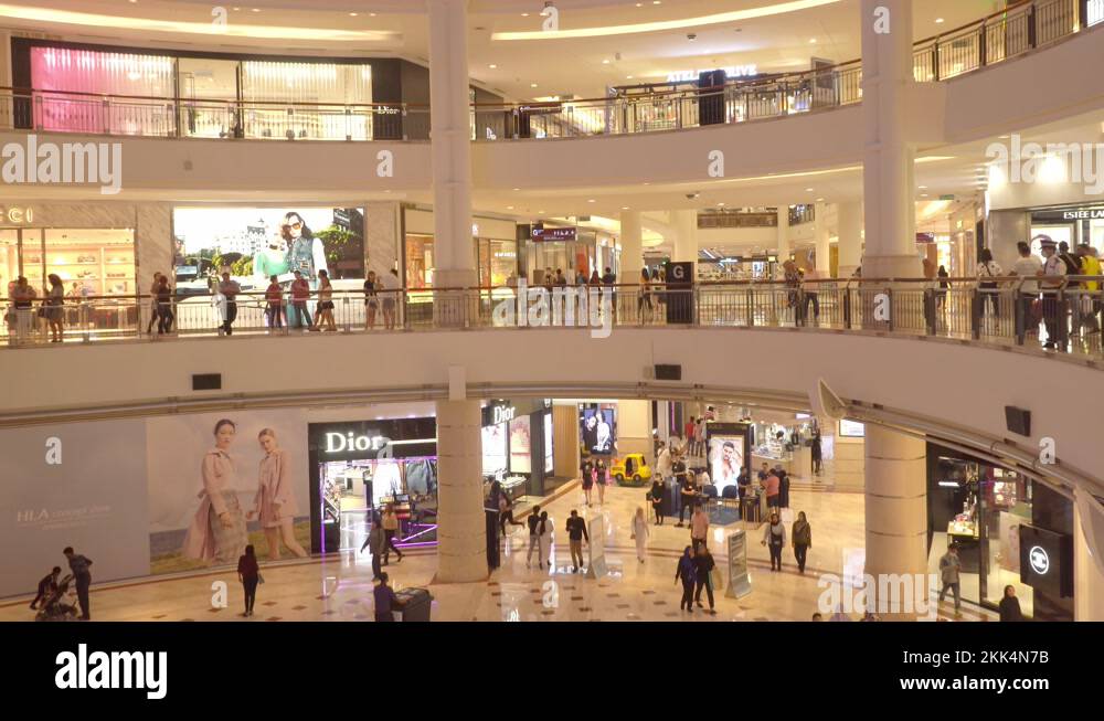 The interior of a large shopping mall. Crowds of people walk shopping ...