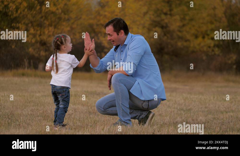 Dad and little daughter say hello. The child claps his father on the ...