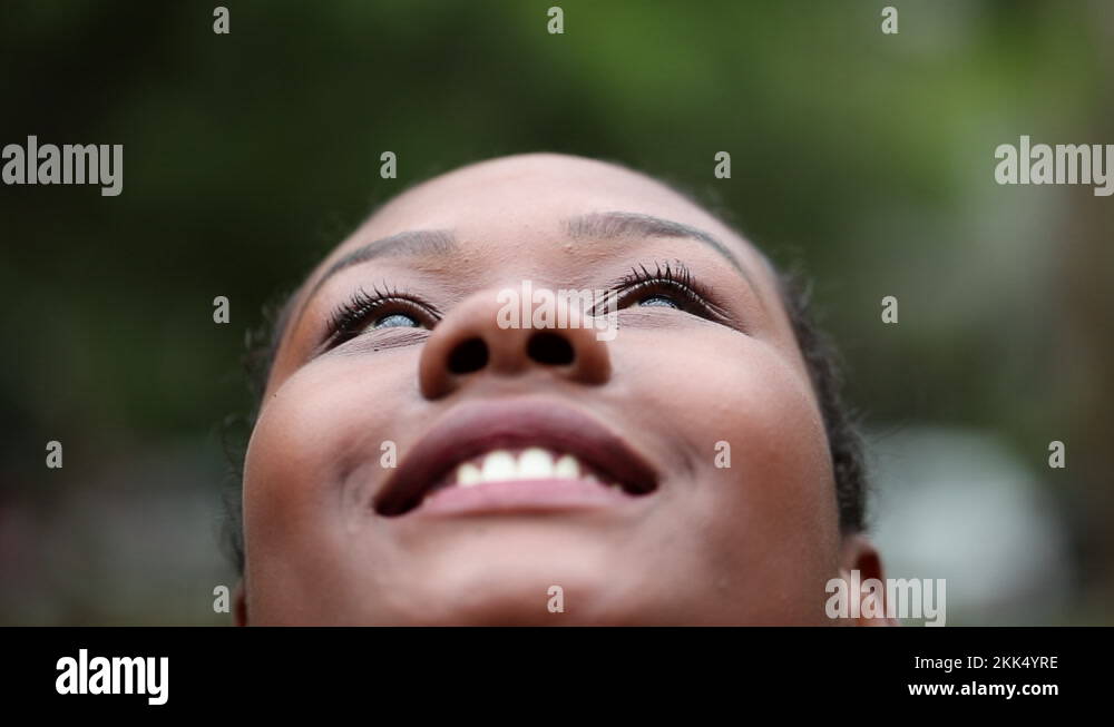 Young African woman face in contemplation loooking up at the sky with ...