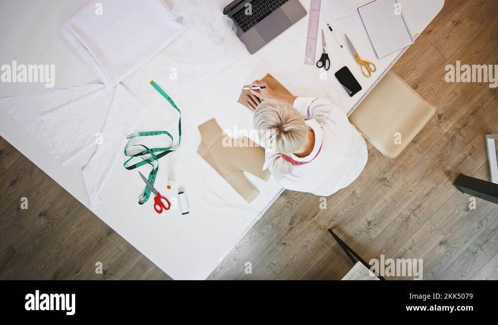 Female, tailor of sewing workshop is drawing pen around pattern which ...