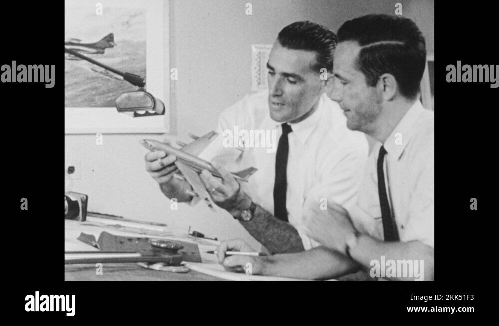 1960s: Two aerodynamics engineers work at drafting table, talking while ...