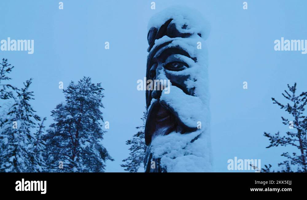 A wooden pole with a man's face carved on it. The camera moves around ...