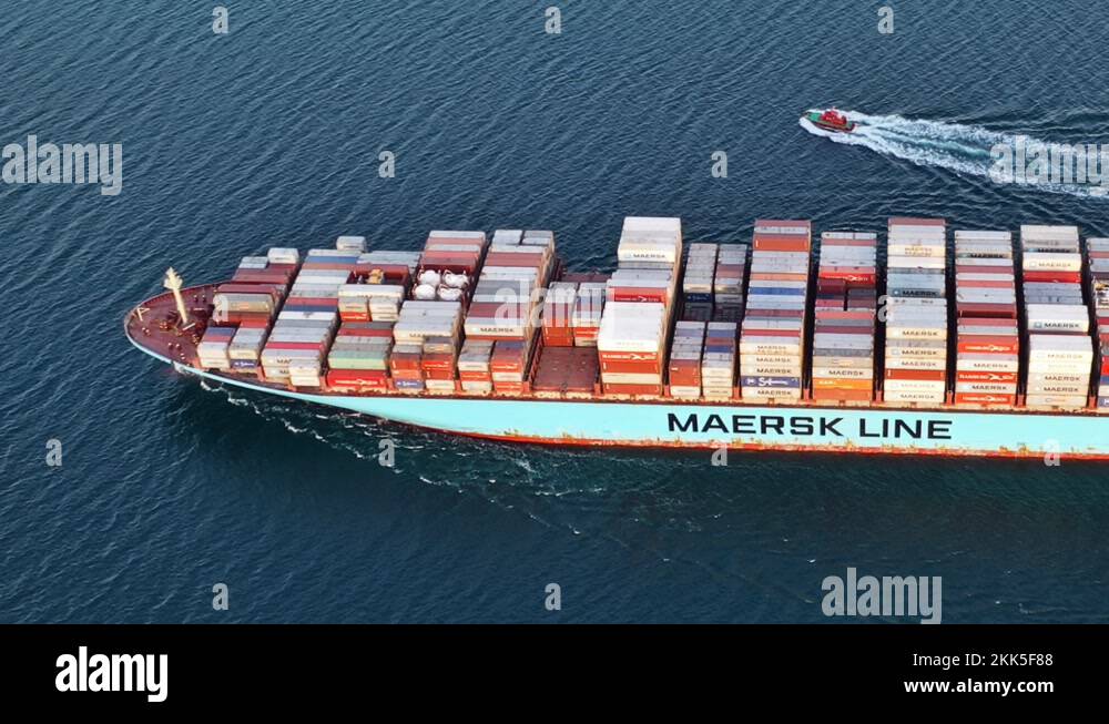 Zoom out. A pilot boat cruising with the huge container ship Stock ...