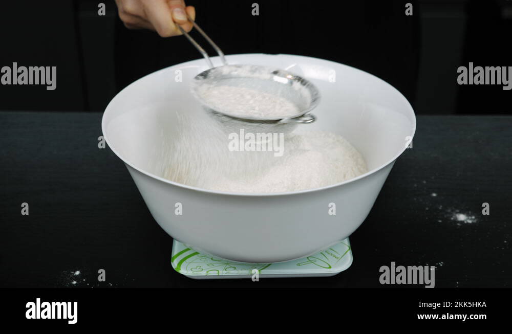 Hand is pouring flour in bowl through sieve. Handmade dough from flour ...