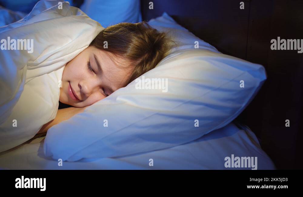 The pretty teen girl naps in bedroom, sees a pleasant sleep and smiles ...