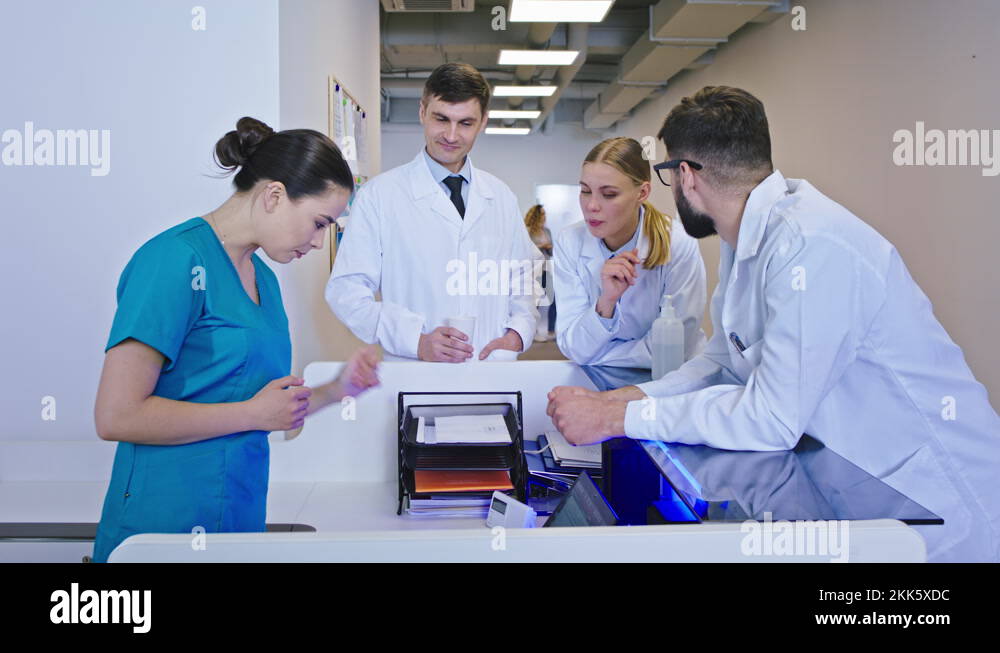 At reception in the modern hospital pretty nurses and group of do have ...