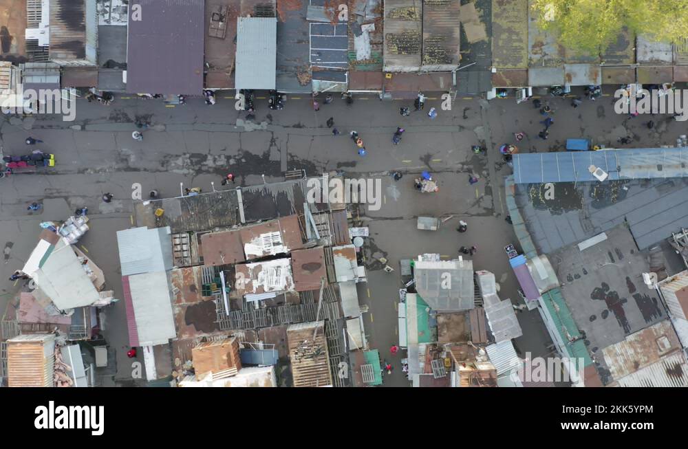 Aerial top-down view of a bazaar in a slums with people between the ...
