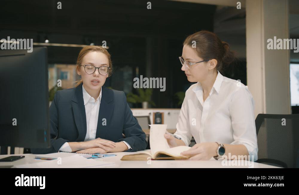 Collaboration of colleagues in office. Two young women in formal suits ...