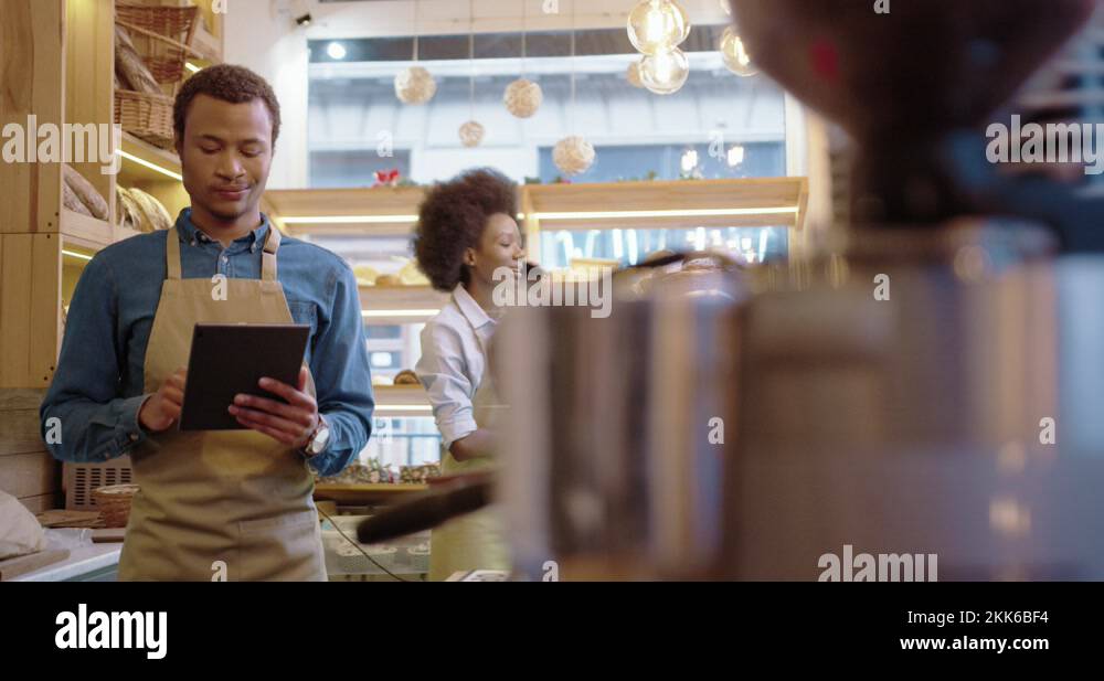 Handsome young African American man seller in bakery shop in apron ...