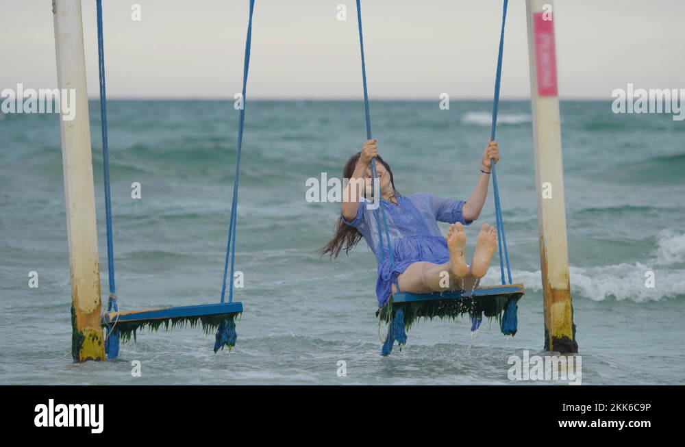 Woman on swing with rope above sea water, happy smile, summer freedom ...