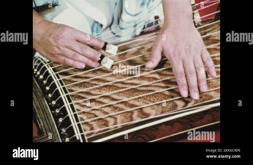 1960s: Woman in kimono speaks. Hands and picks pluck and play strings ...