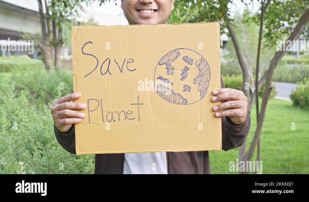 An Asian man walking down the street, raising a protest sign with the ...