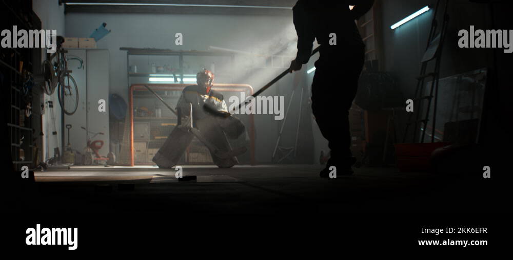 Father training his son hockey goalie, practicing hockey shots inside ...