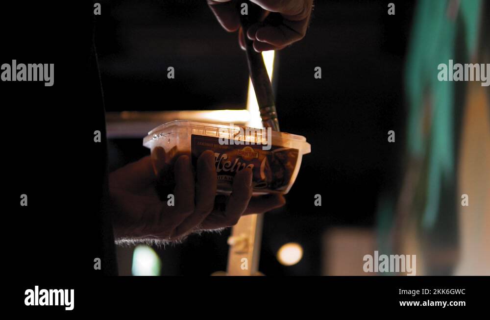 Slow motion of street art at night. Man is drawing with brush on the ...