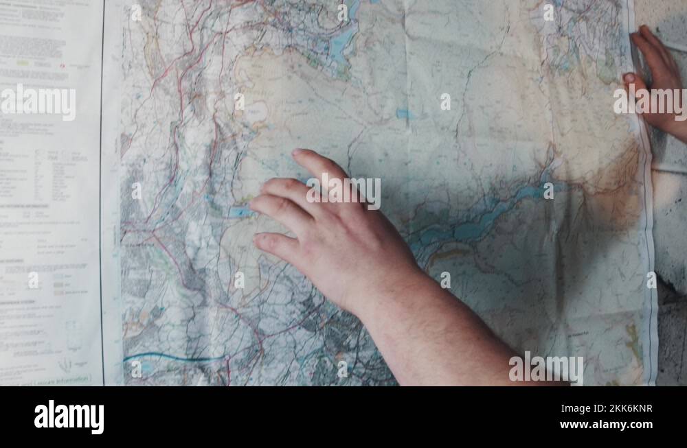 A man searching for a location on a wall map. His finger points to a ...