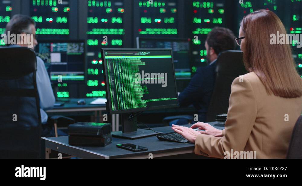 Beautiful female programmer sitting at desktop in office with servers ...