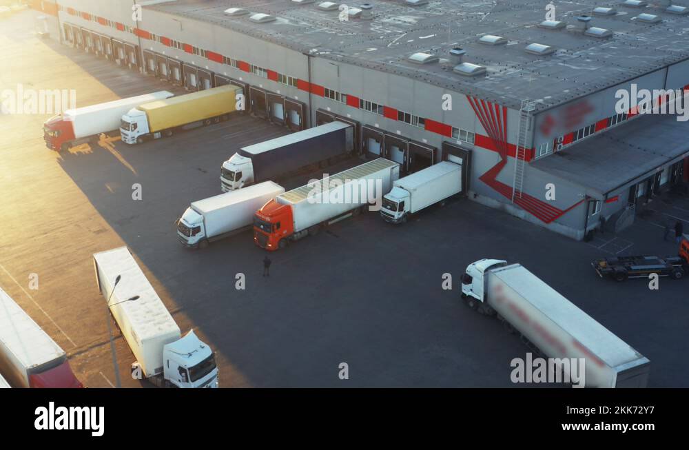 Trucks with semi-trailers stand at warehouse ramps in the logistics ...