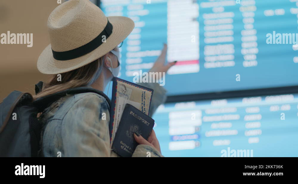 Woman looking at flight timetable and searching flight in airport ...