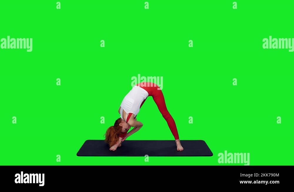 Athletic fit woman stretching on mat during yoga against green screen ...