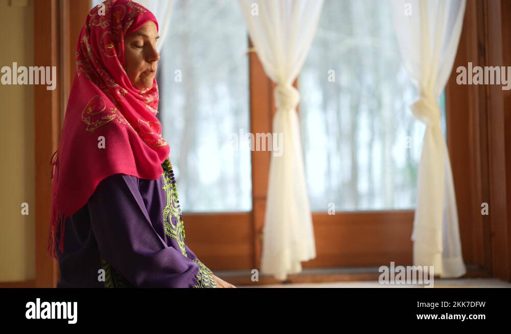 Mature Muslim woman praying at home with beautiful light with snow on ...