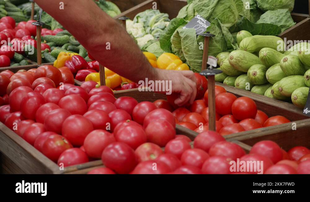 Close-up hands of grocery worker is arranging vegetables on store ...