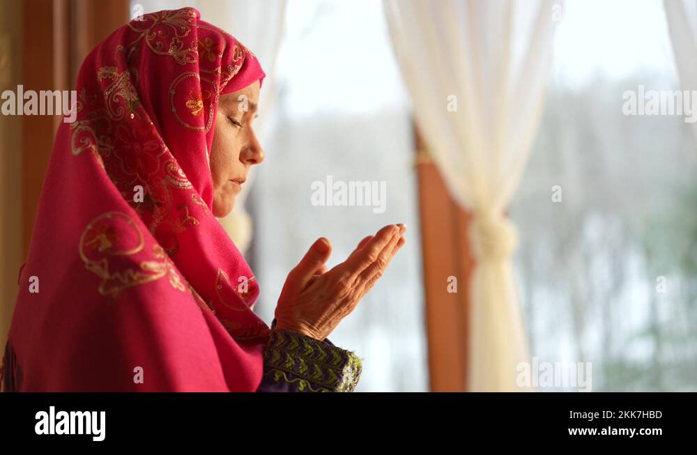 Mature Muslim woman praying at home with beautiful light with snow on ...