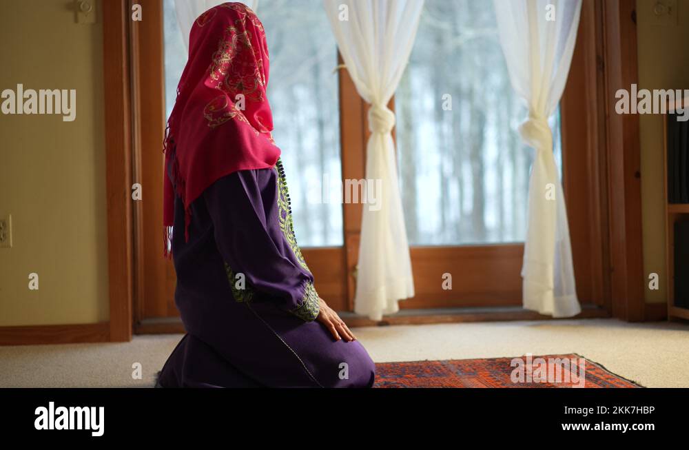 Mature Muslim woman praying at home with beautiful light with snow on ...