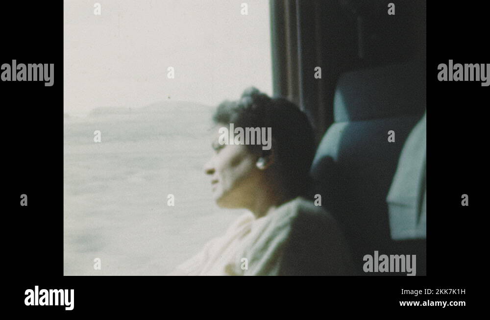 1950s: Woman looks out window, riding on train. Looking out window of ...