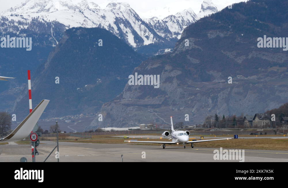 Luxury private jet on taxiway at Sion airport, with snowy alps in the ...
