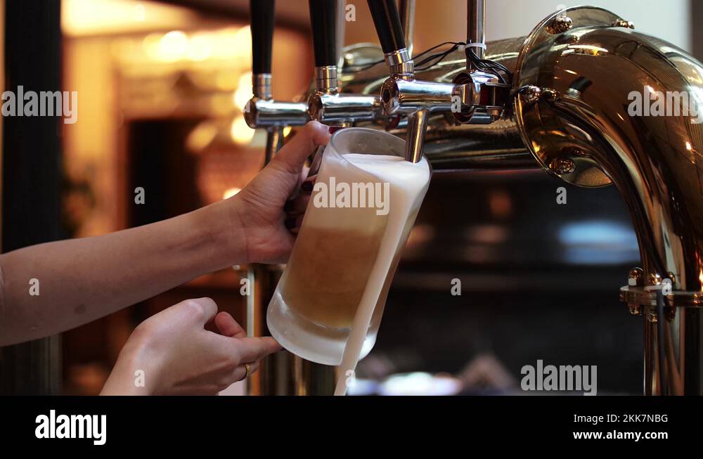 Bartender pouring draft beer in a glass. Beautiful white beer foam ...