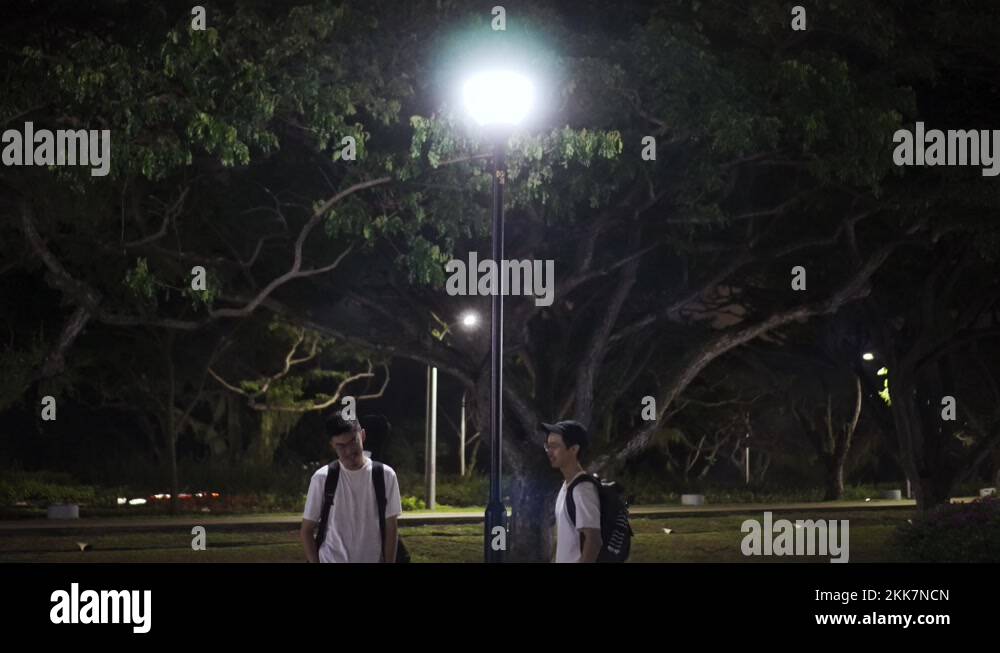 Two friends chatting happily under a lamp post at East Coast Park Stock ...