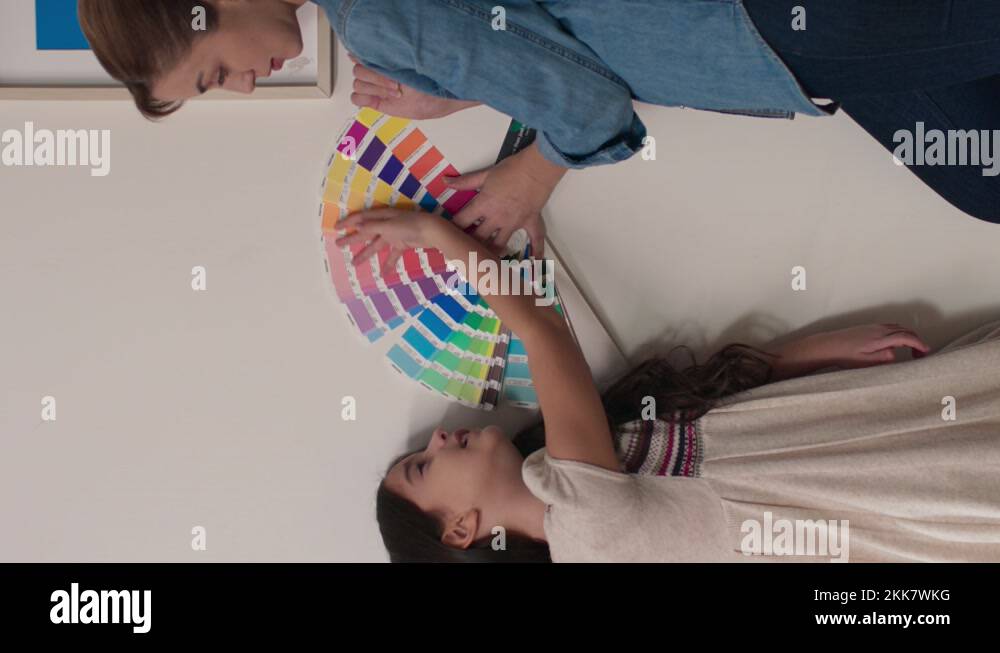 Young mother and daughter choosing colors for wall painting in new home ...