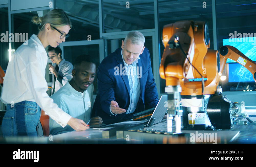 Two engineers explaining the third one industrial robot functions and ...