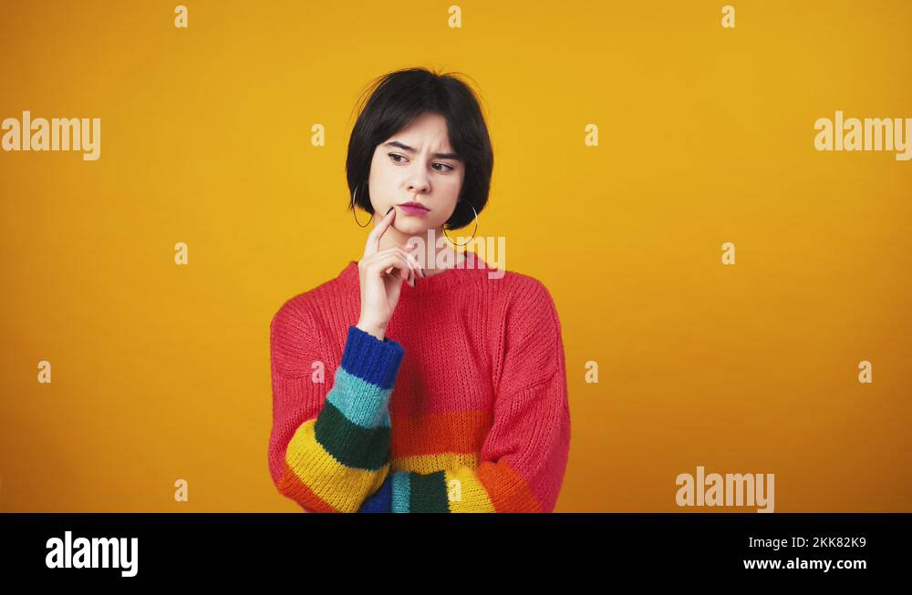 Thinking process. Young cute lady contemplating over orange studio ...