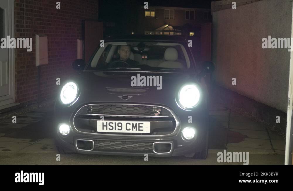 Mini cooper car driving into private garage at night with headlights on ...