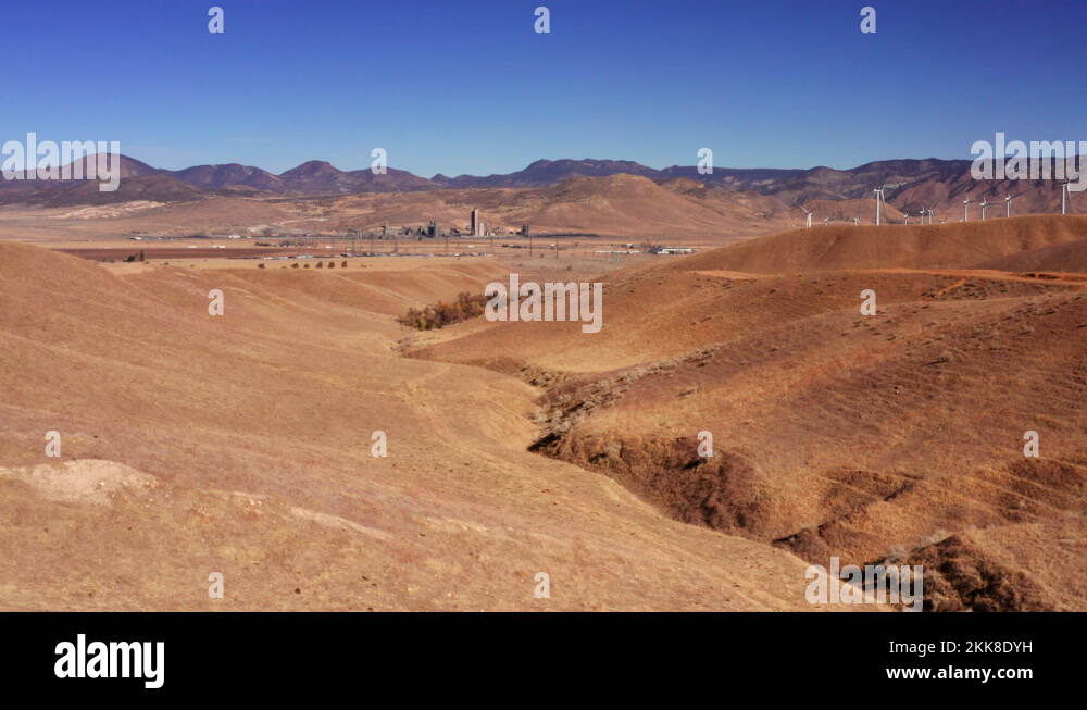 Arid grassland, hills, mountains, rural farming land and wind turbines ...
