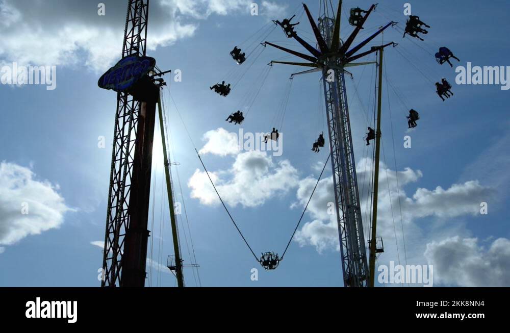Huge fairground rides back lit in the UK sun in slow motion. Reverse ...