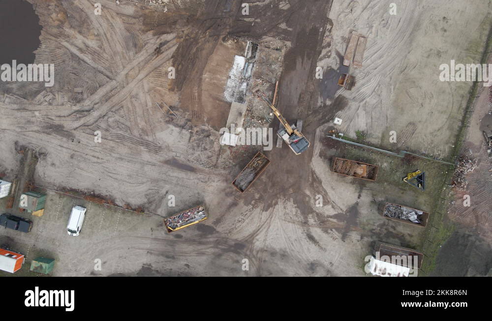 Top down aerial of excavator collecting rubble from demolished building ...