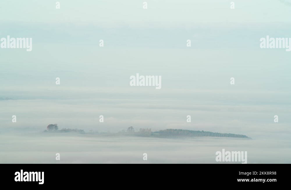 Layers of mist in a valley in the countryside with hills, green fields ...