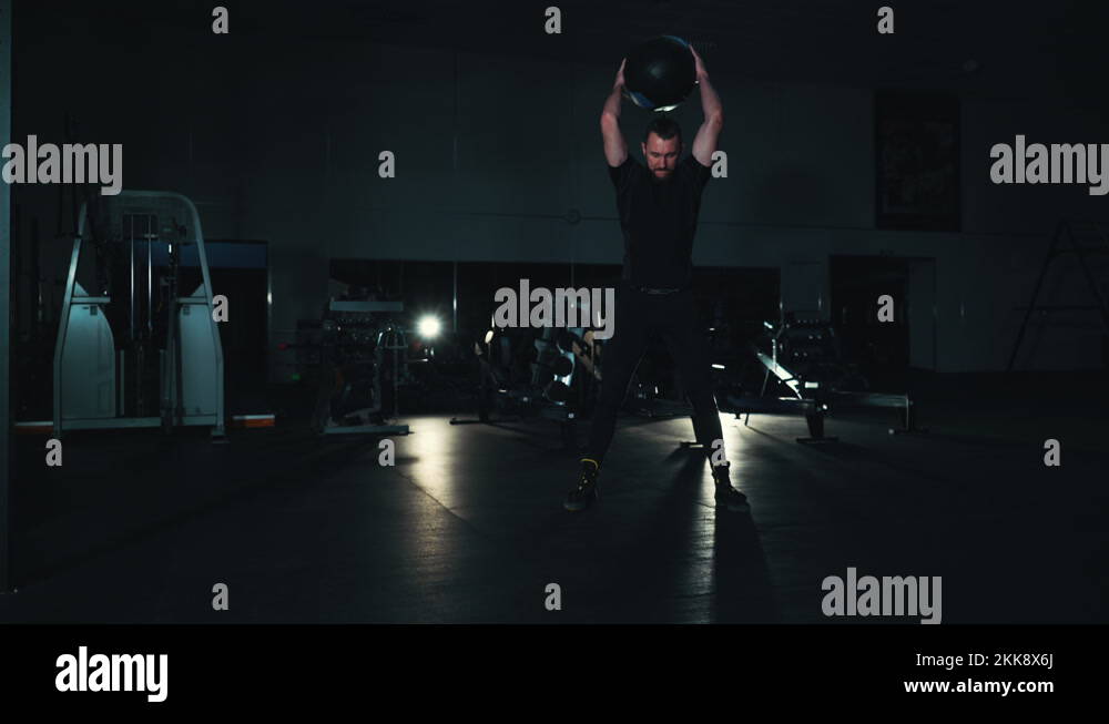 Fit man throwing heavy ball in dark gym Stock Video Footage - Alamy