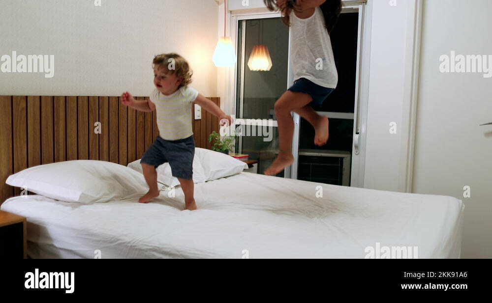 Children jumping up and down on bed. Active happy kids bouncing, little ...