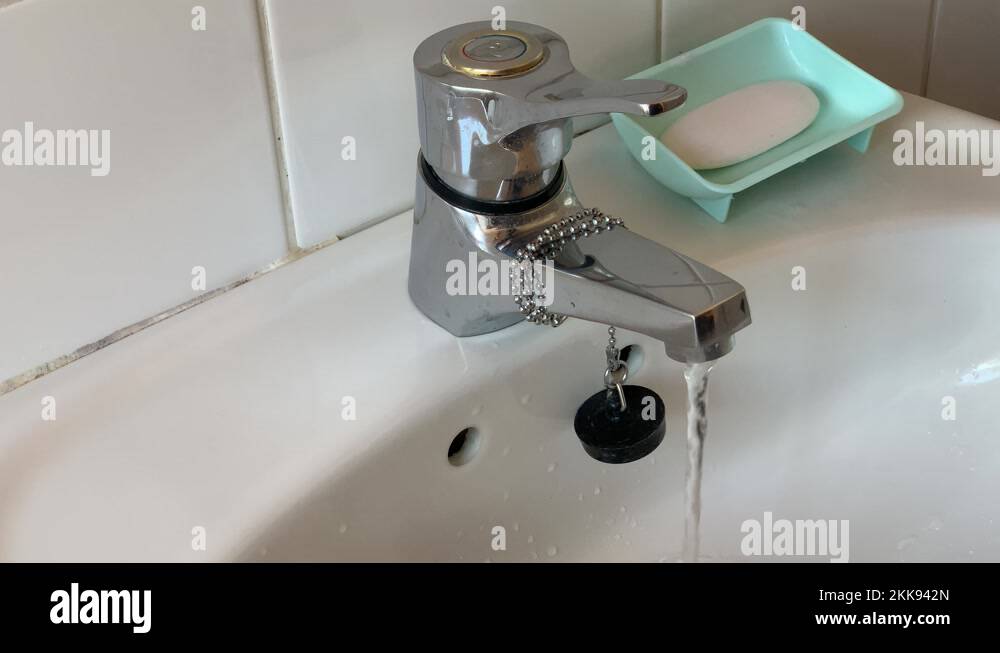 Open water tap in the bathroom and a bar of white soap for washing ...
