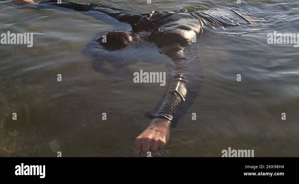 Drowned man with long dark hair lying face down in shallow water Stock ...