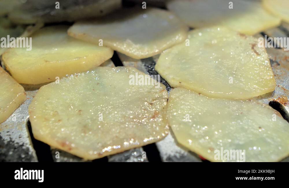 Korean style BBQ in restaurant. Potatoes slices cooking on Korean BBQ ...