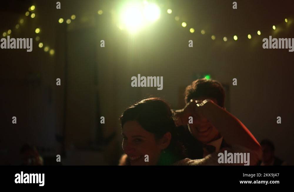 Newly married couple dance together in the colourful lights at their ...