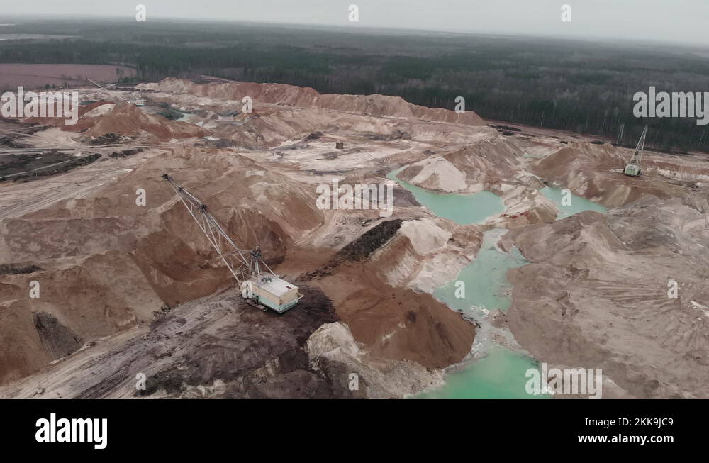 Deep huge mining quarry with huge mounds of minerals. Excavator works ...