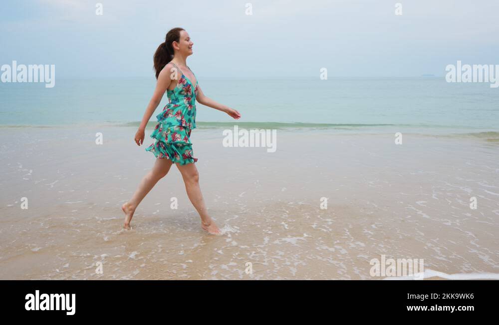 Cheerful lady walk at beach, water splash on steps, tracking shot Stock ...